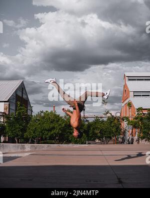 Urban athlete breakdancer performing somersault jump flip at skate park ...