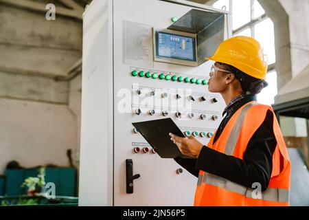 Black woman wearing helmet and vest working with tablet computer in ...