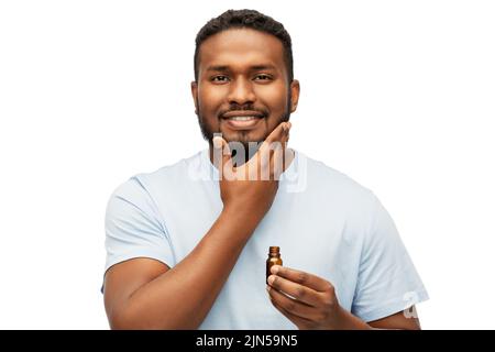 african man applying grooming oil to beard Stock Photo - Alamy