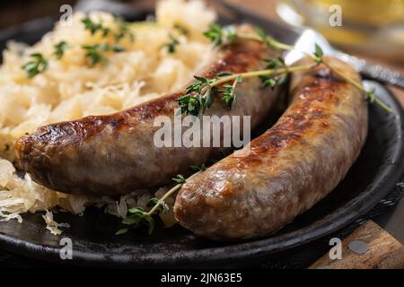 Closeup of fried bratwurst garnished with thyme on a plate on a rustic ...