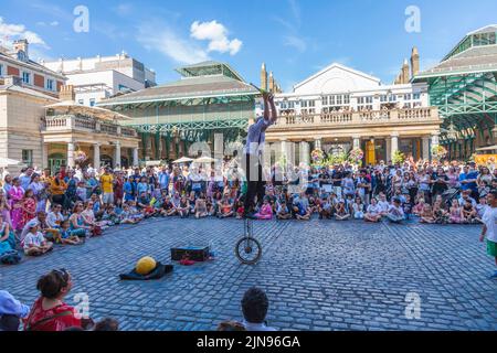 A male juggler entertaining crowds on a unicycle in Covent Garden ...