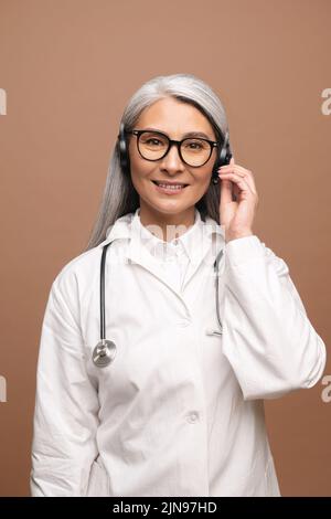 Asian female doctor talk phone call consult patient holding clipboard ...
