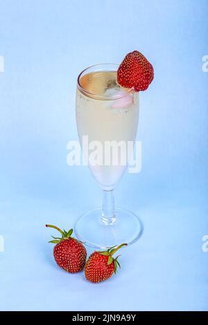 A misted glass of champagne and fresh strawberries on a blue background ...