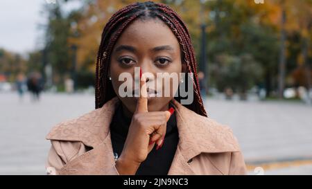 Young woman showing silence gesture while posing with pink balloons ...