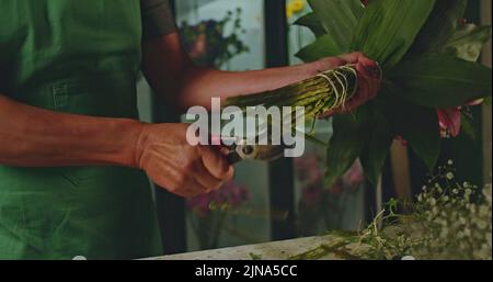 Florist trimming plants creating bouquet of flowers for client order ...