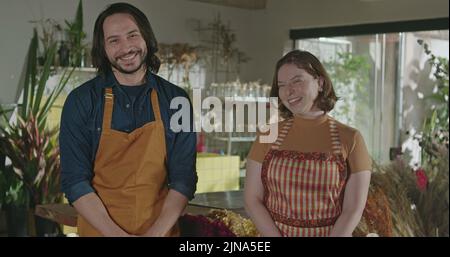 Portrait of two floriculture professionals inside flower shop. Male and ...