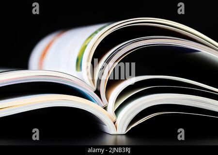 A part of a stack of open magazines on dark background Stock Photo - Alamy