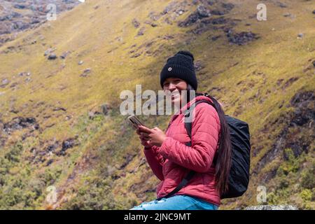An attractive hiker sitting and holding a phone in the beautiful ...