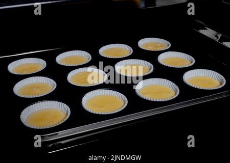 Uncooked homemade cupcakes, muffins in electric oven, black background ...