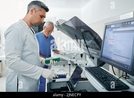 Laboratory technicians analyze blood samples near biochemical automatic ...