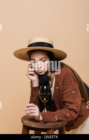 Trendy woman in cardigan and straw hat holding ripe apple while sitting ...