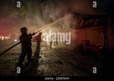 A Sag Harbor firefighter trains a hose stream through a doorway onto ...