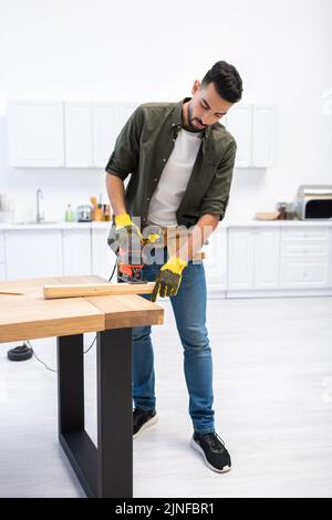bearded carpenter with tape measure using smartphone in workshop ...