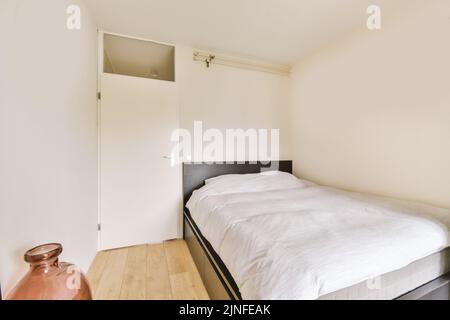 Comfortable bed located near glowing lamp and framed pictures in ...