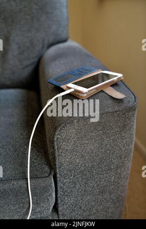 mobile phone recharging on arm of chair inside house hertfordshire ...