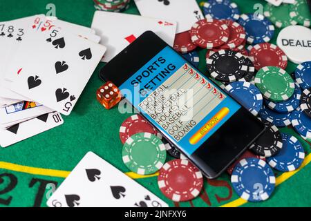 Smartphone with poket table on screen, playing cards and chip cards on ...