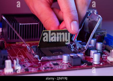 A man's hand inserts a processor into the motherboard socket Stock ...