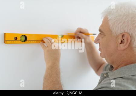 senior man measuring wall with construction level Stock Photo - Alamy