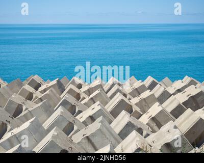 Concrete breakwaters and heaps of stones on the shore. Stone against ...