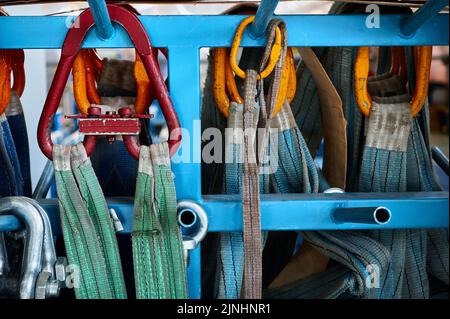 Rigging equipment with strops hangs on rack in warehouse Stock Photo ...