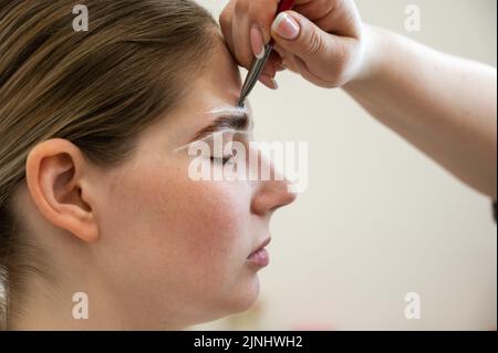 The master draws the shape of the eyebrows with white paint before ...