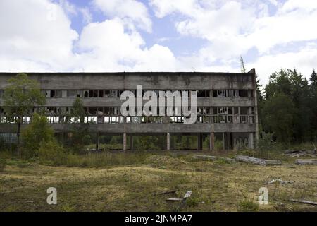 ruined industrial building on stilts with a broken wall of glass ...