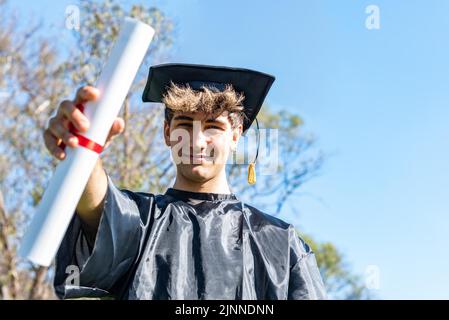Happy graduated man wearing a bachelor gown and a black mortarboard and ...