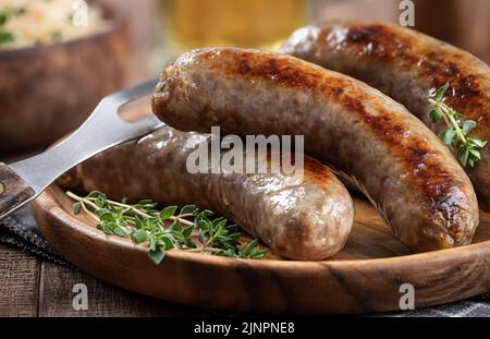 Closeup of fried bratwurst garnished with thyme on a plate on a rustic ...