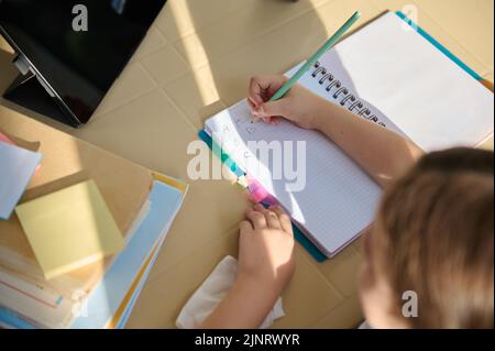 Details: Hand of schoolgirl, first grader holding pencil, making notes ...