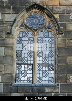 contrasting patterns in ancient glass of arched mullion window above ...