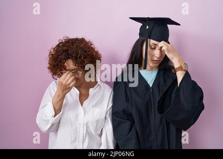 Hispanic mother and daughter wearing graduation cap and ceremony robe ...