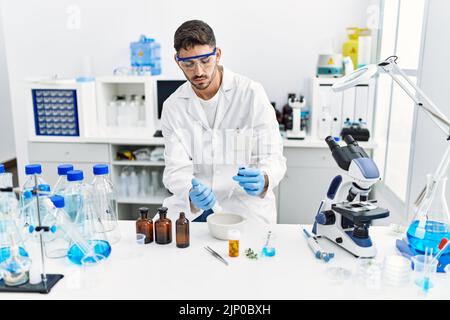Handsome hispanic man using scientific mortar at laboratory Stock Photo ...
