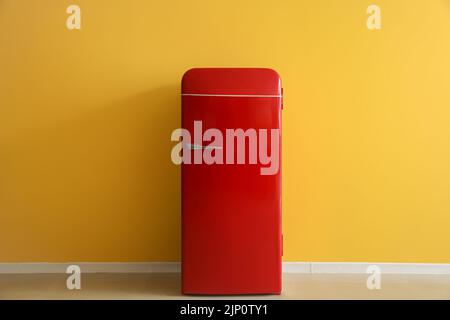 Stylish retro fridge near yellow wall Stock Photo - Alamy