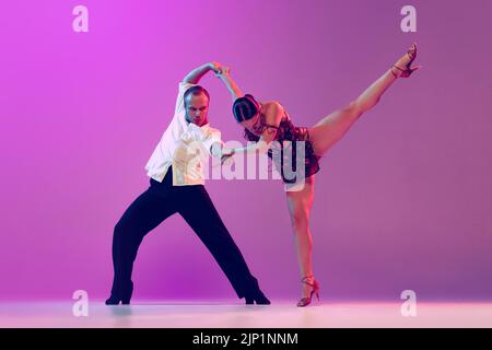 Two young graceful dancers wearing black stage outfits dancing ballroom ...