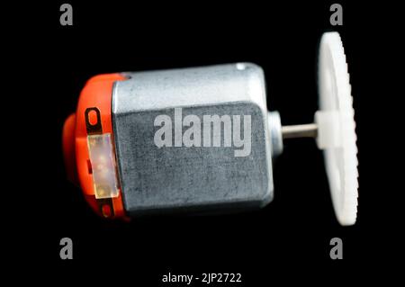 Direct current electric motor with white gear attached to it shaft on a ...
