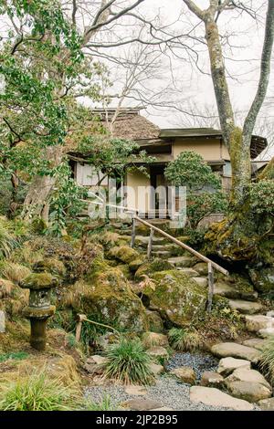 Entrance to traditional Japanese garden with stone path and tile roofed ...