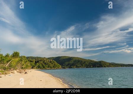 A mesmerizing view of the sandy Bon Bon Beach and a cliff with dense ...