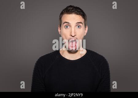 grotesque face with open mouth of an adult man isolated on grey ...