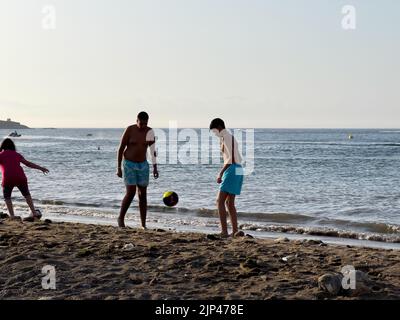 Two male friends play football on the beach Stock Photo - Alamy
