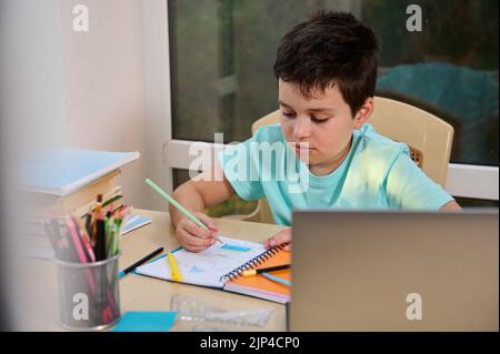 child, schoolboy solves math examples in a column, makes arithmetic ...