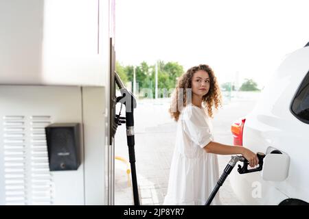 Young curly woman refueling car at gas station Stock Photo - Alamy