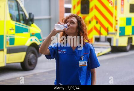 An NHS doctor cools off with a drink of water during a break at a ...