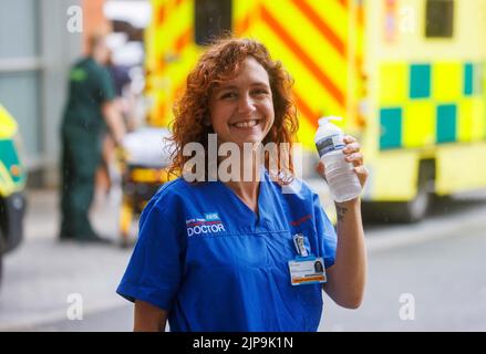 An NHS doctor cools off with a drink of water during a break at a ...