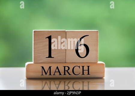March 16 calendar date text on wooden blocks with blurred park ...