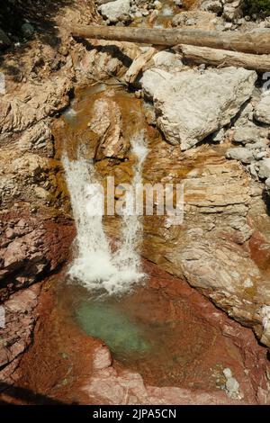 A scenic vertical shot of a waterfall surrounded by greenery in the ...