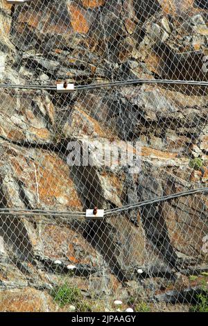 Draped mesh rockfall barrier along Stock Photo - Alamy