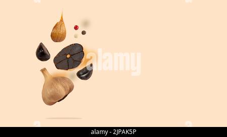 Black garlic bulbs fly in the air on a beige background. An image of ...