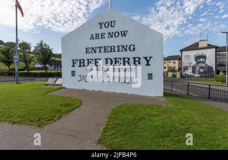 Sign entering Free Derry with mural by Bogside Artists on side of house ...