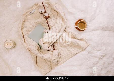 Flat lay scene with knitted warm sweater, candle and coffee on the bed ...