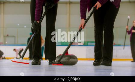 Curling training - leading granite stone on the ice - two women rubbing ...